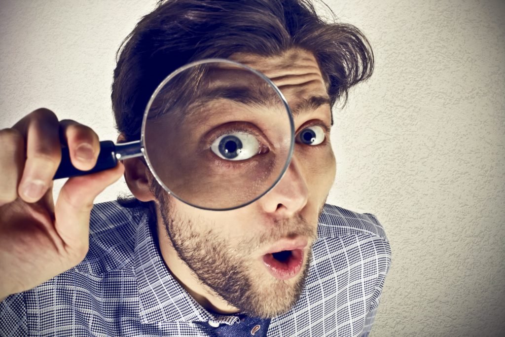 Businessman looks through a magnifying lens - Wasabi Publicity